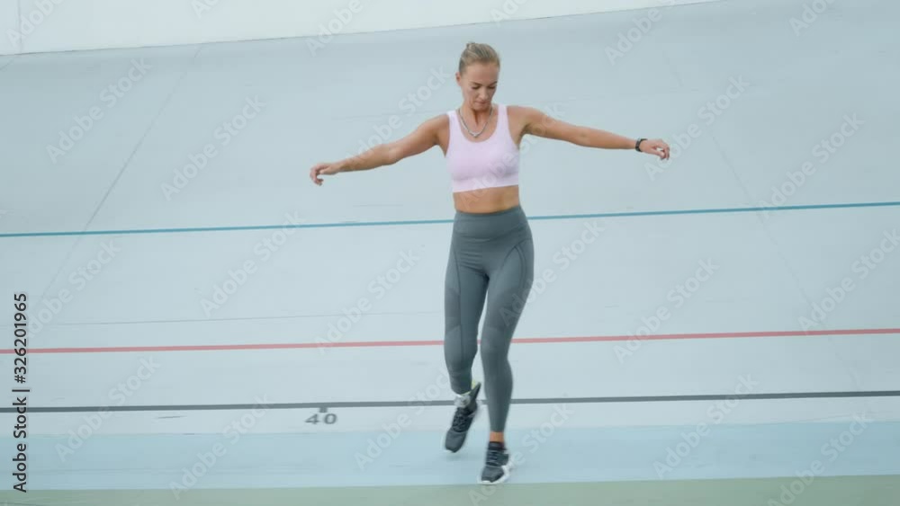 Athlete with prosthetic leg jumping sideways on track. Girl training at ...