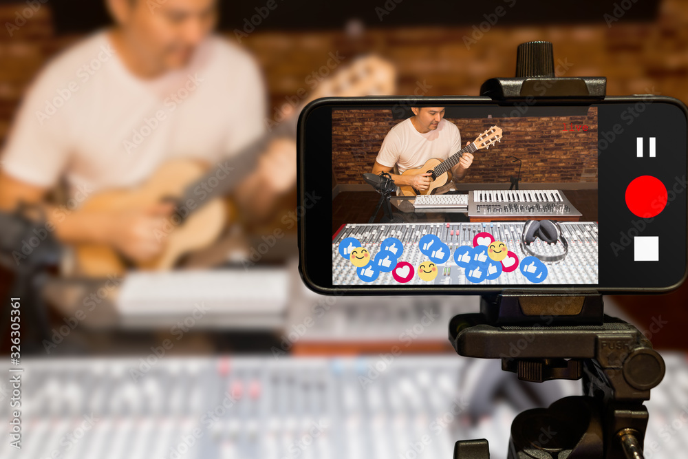 music vlogger streaming a live video while playing acoustic guitar in ...