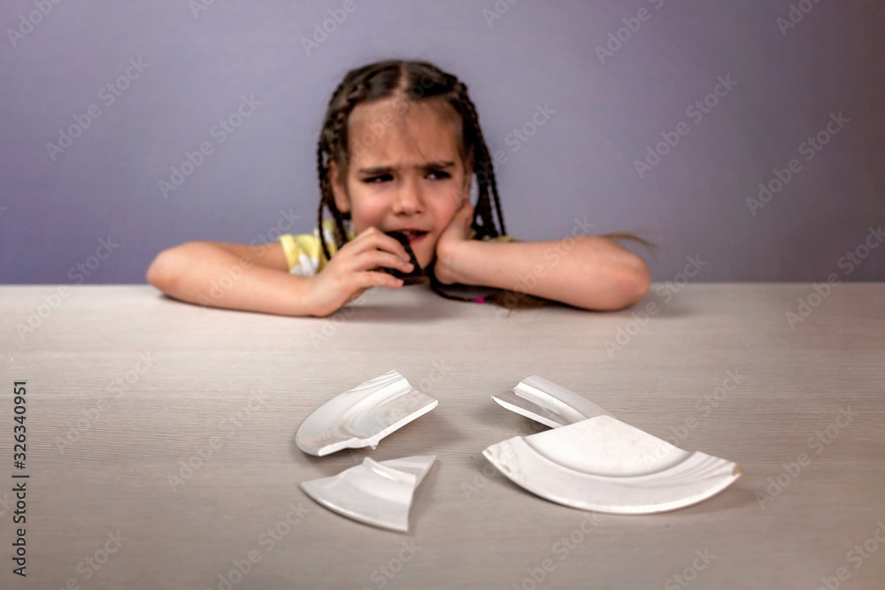 Girl sitting before broken plate and eating chocolate bars with ...