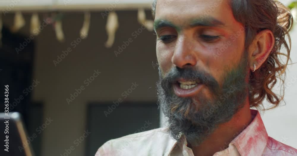 Indian man with black hair and beard, like guru yogi baba, using a smart phone touch screen ...