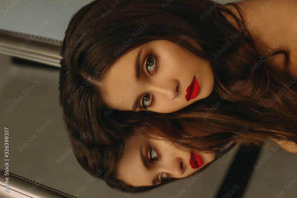 Model posing near the mirror stares intently at camera. Closeup ...
