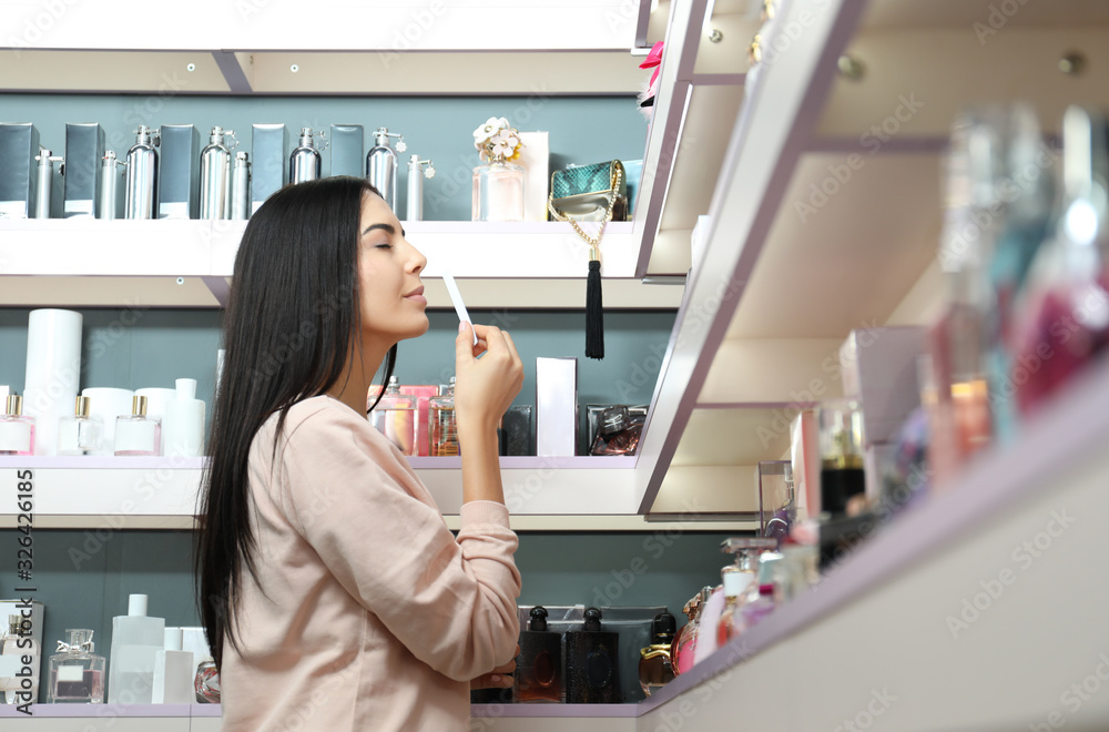Beautiful young woman choosing perfume in shop Stock Photo | Adobe Stock