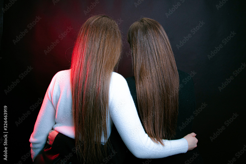 Long, beautiful hair. Two girls hugging. Studio, black background Stock ...