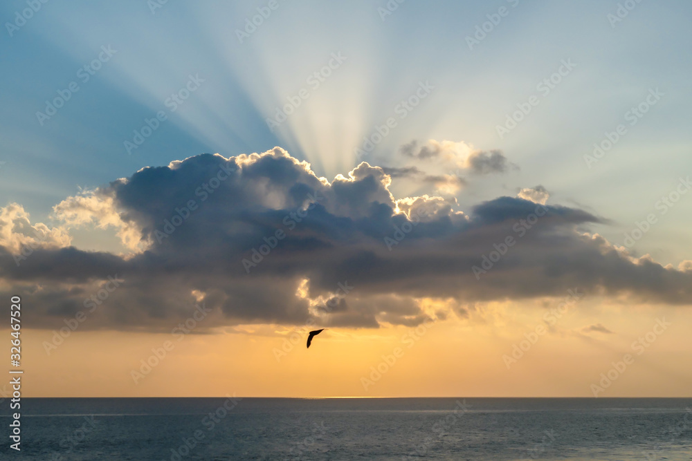 Sunset over the sea in Bali, Indonesia. There is a cloud, behind which ...