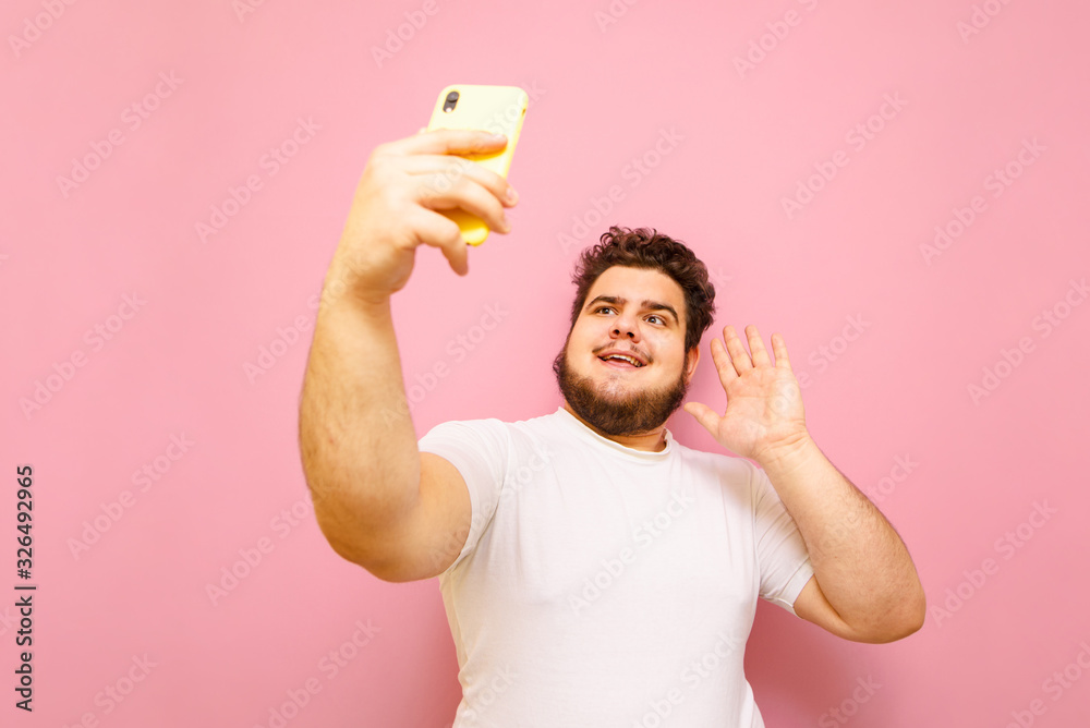 Funny fat man with a beard holds a smartphone in his hand and phone ...