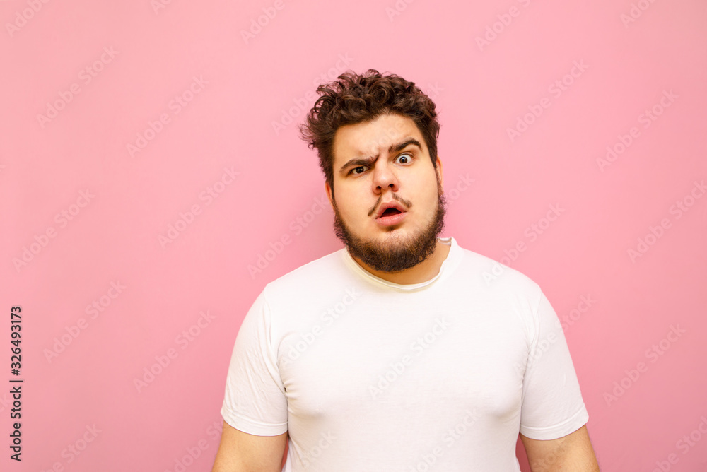 Portrait of surprised young man in white t-shirt and overweight on pink ...