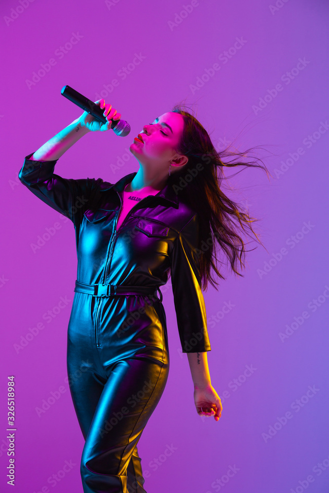 Caucasian female singer portrait isolated on purple studio background ...