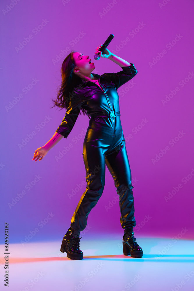 Caucasian female singer portrait isolated on purple studio background ...