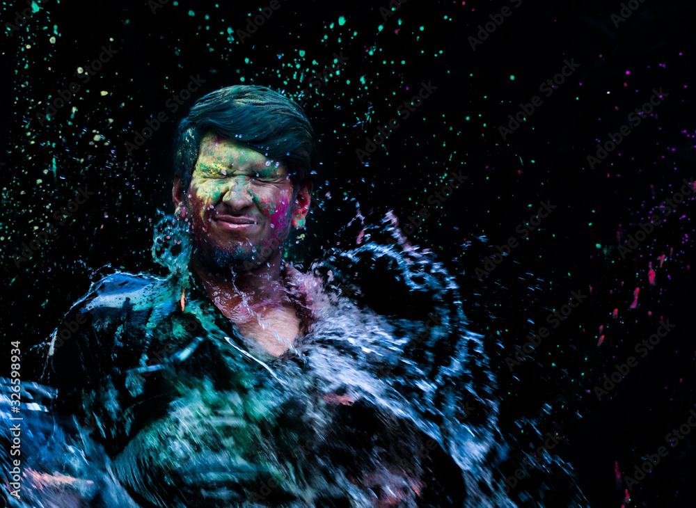 Foto de Young man playing holi with water. water splashing on his face ...