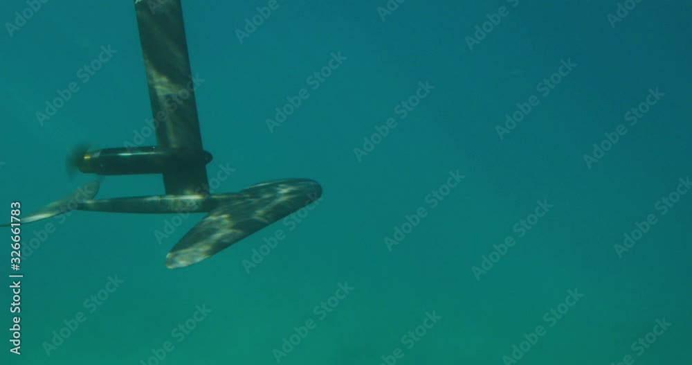Under over view of a surfer hanging five on an electric hydrofoil ...