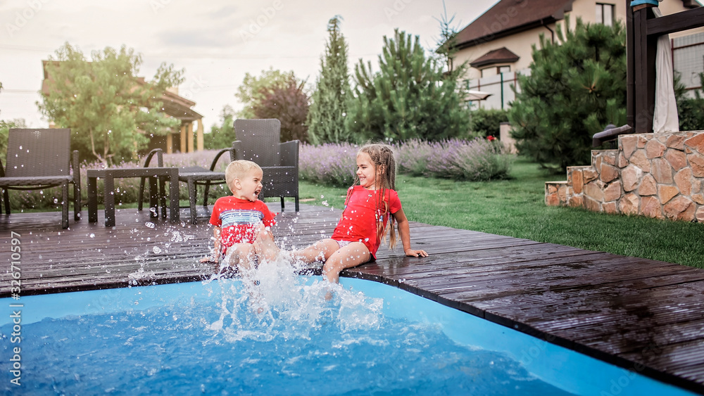 Happy cute sibling, boy and girl, have a fun and splashing each other ...