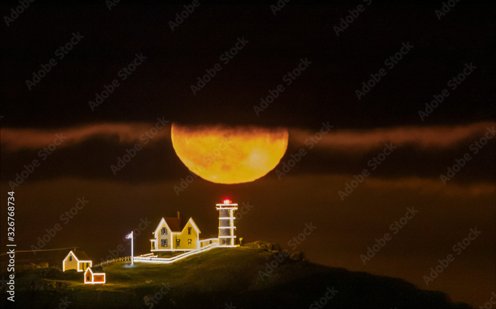 Full Moon Rises Above the Nubble Lighthouse in Maine before sliding ...
