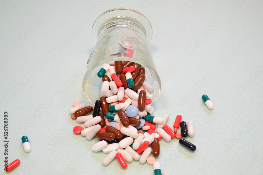 Many drug and pill spilled out of a glass on light background. Rational ...