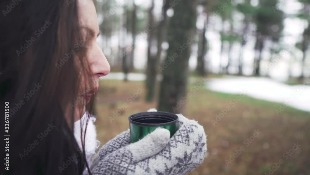 Woman drinking tea in the forest. The girl drinks tea from a thermos ...