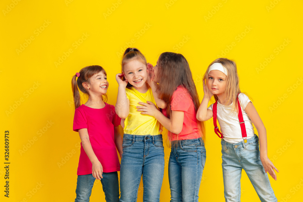 Secrets. Happy children playing and having fun together on yellow ...