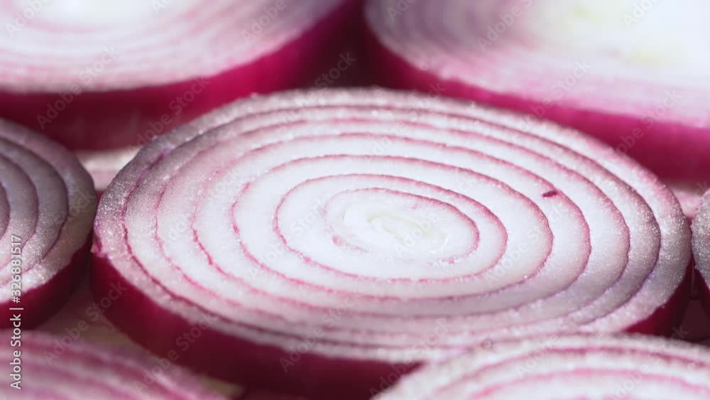 Sliced red onion rings rotating on white in 4K. Closeup top view of ...