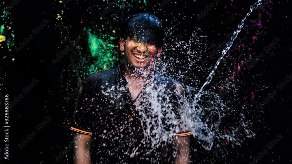 Foto de Young man playing holi with water. water splashing on his face ...