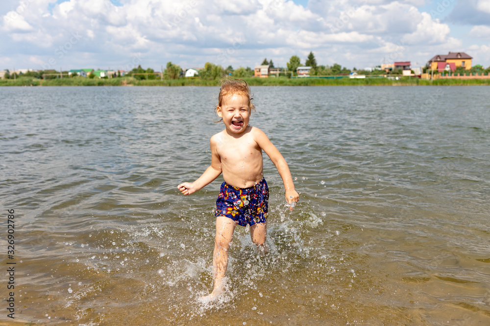 Joyful child frolics in the water. drops splashing water Stock Photo ...