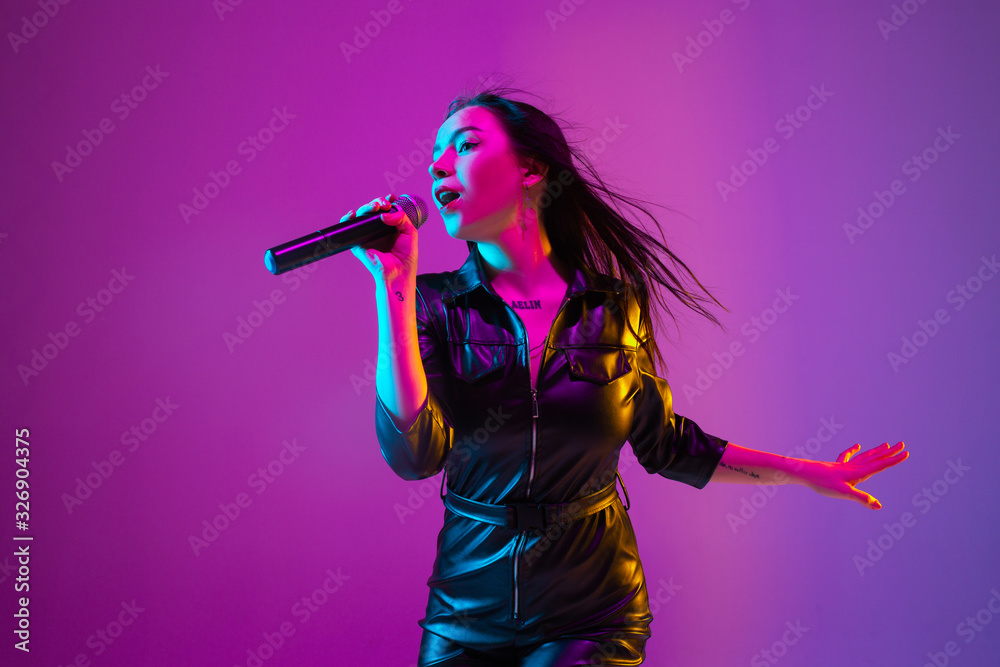 Caucasian female singer portrait isolated on purple studio background ...