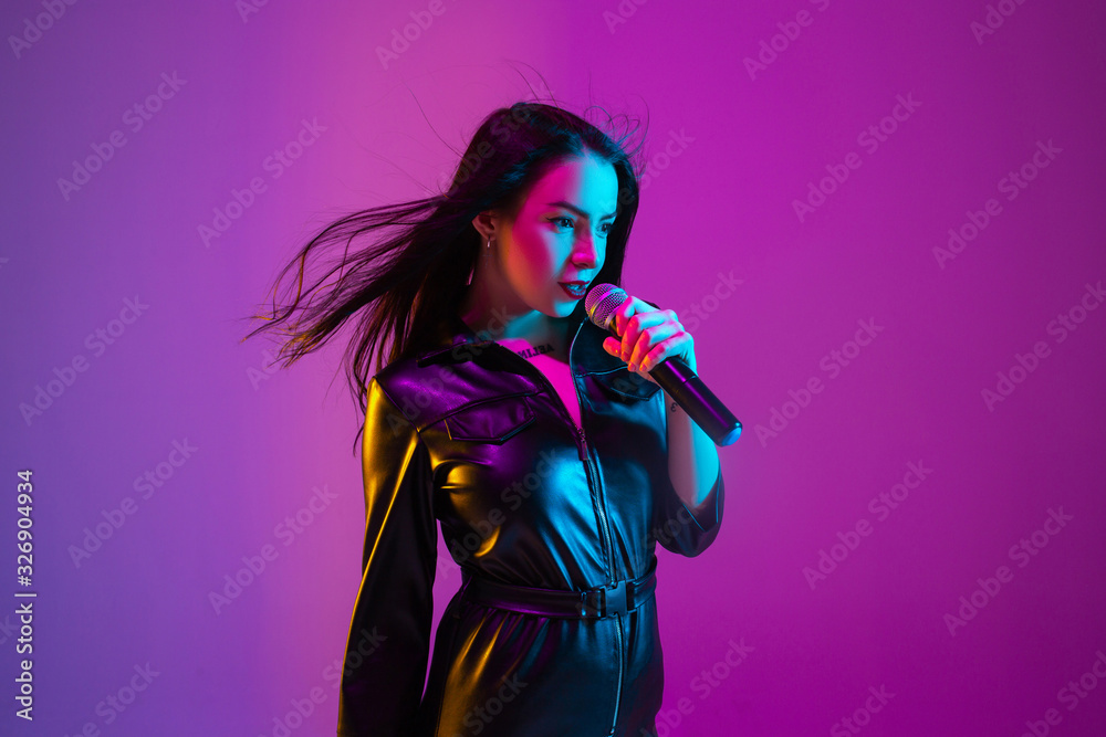 Caucasian female singer portrait isolated on purple studio background ...