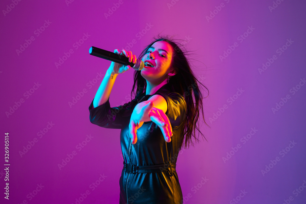 Caucasian female singer portrait isolated on purple studio background ...