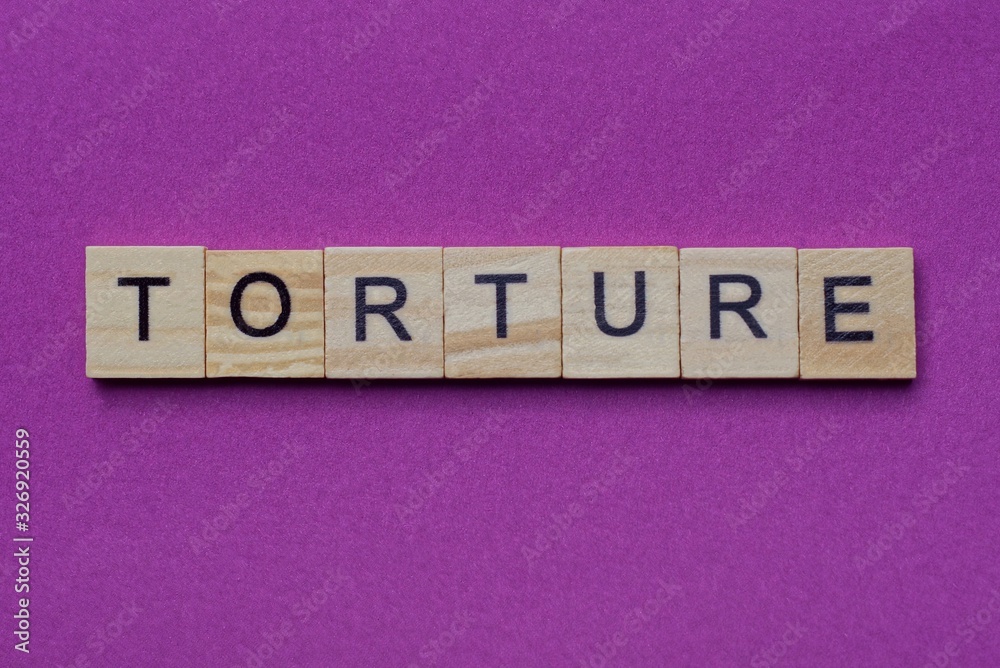 word torture from small gray wooden letters lies on a lilac background ...