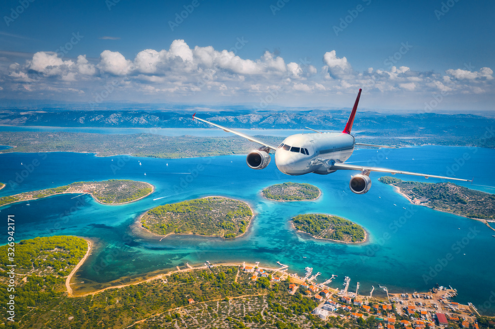Airplane is flying over small islands and sea at sunny day in summer ...