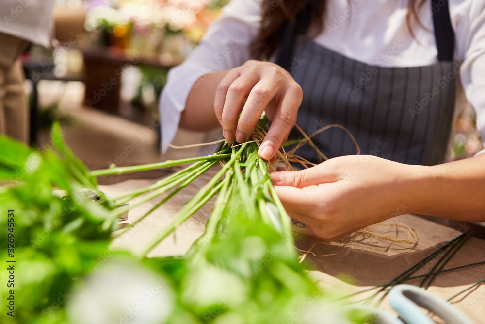 Hands of florist in flowers tying with raffia Stock Photo | Adobe Stock