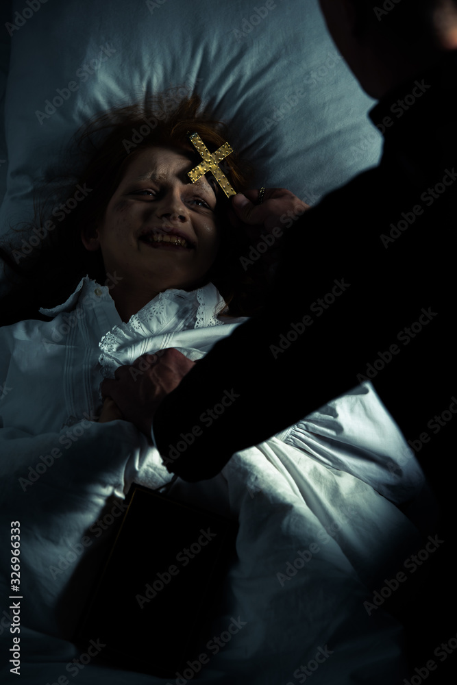 exorcist holding cross over female demon in bed Stock Photo | Adobe Stock