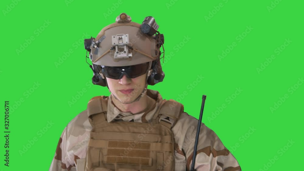 Young soldier walks, holds a radio station and gives orders on a Green ...