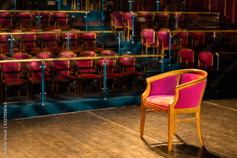 Red upholstered chair on a theater stage with reflectors ray with a ...