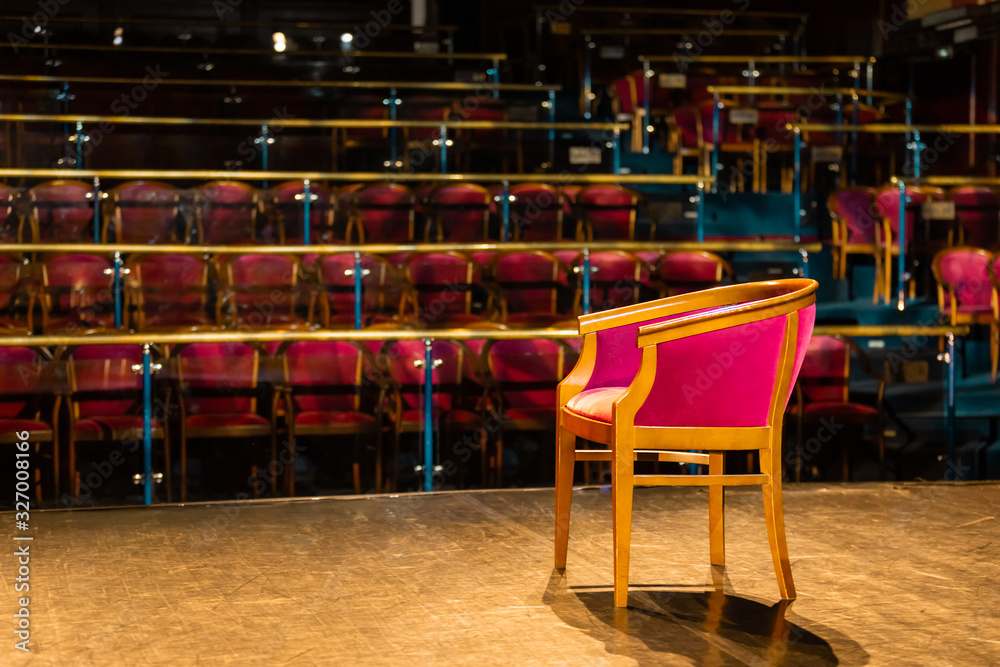 Red upholstered chair on a theater stage with reflectors ray with a ...