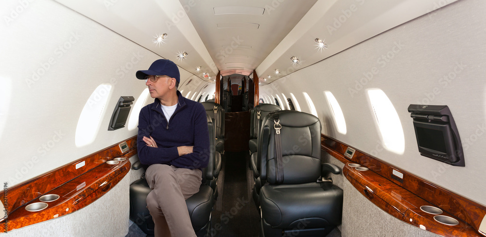 Handsome man sitting inside a private jet alone. Stock Photo | Adobe Stock