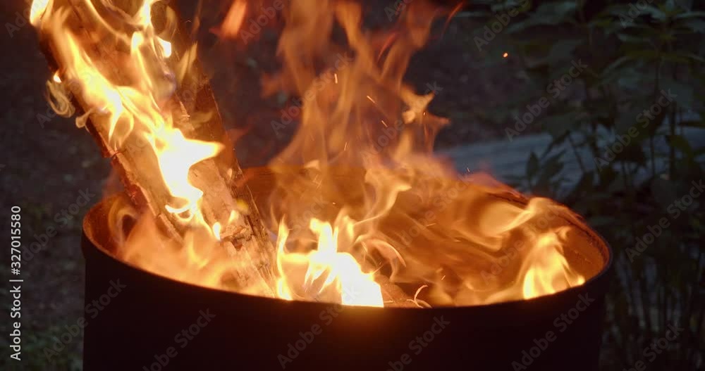 Firewood is burning in a round iron barrel. Homeless people are warming ...