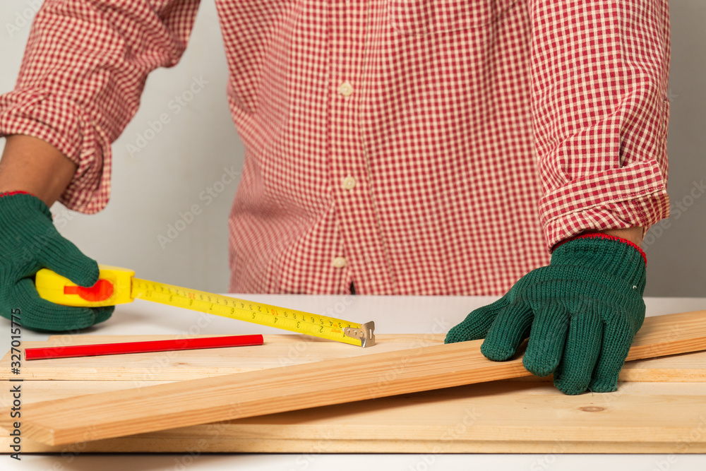 joiner measuring a wooden plank with tape measure yellow on the work ...