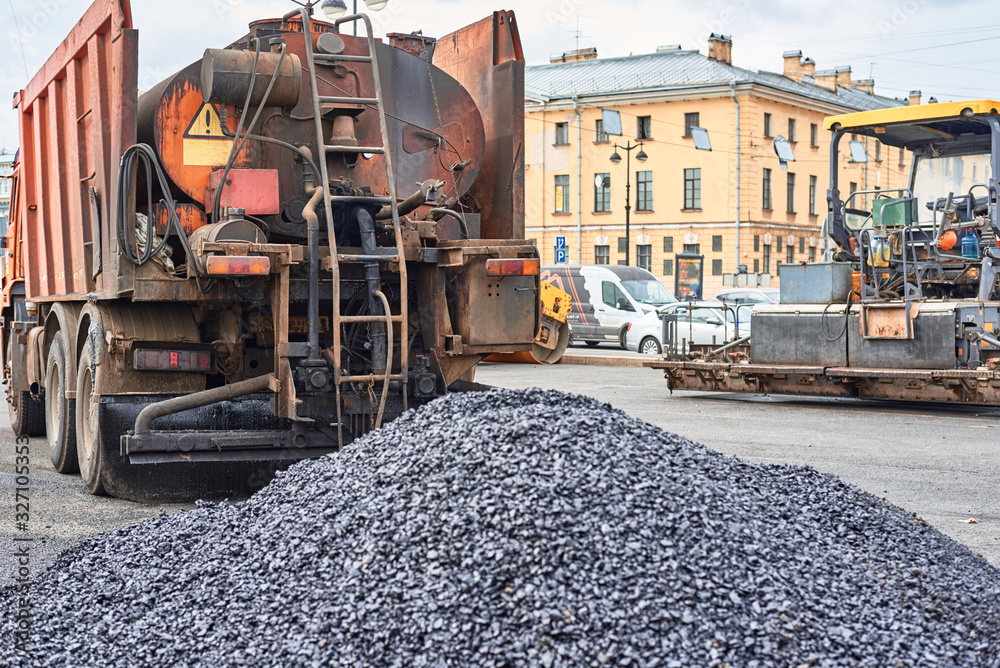 Hot asphalt and trick with a bitumen in city. Road construction Stock ...