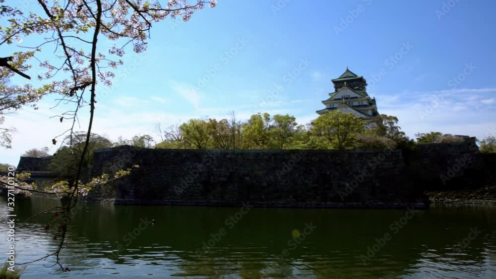 4K, Main tower of Osaka Japanese Castle behind rock wall and the moat ...