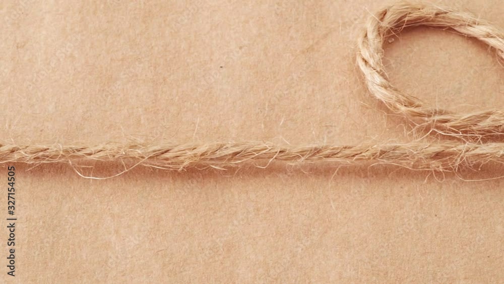 Twine tied in a bow on brown paper package, close shot. Dolly shot of ...
