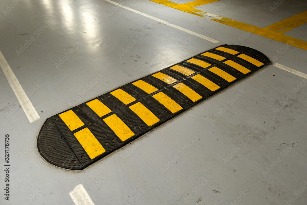 Striped black and yellow speed bump on a road. Stock Photo | Adobe Stock