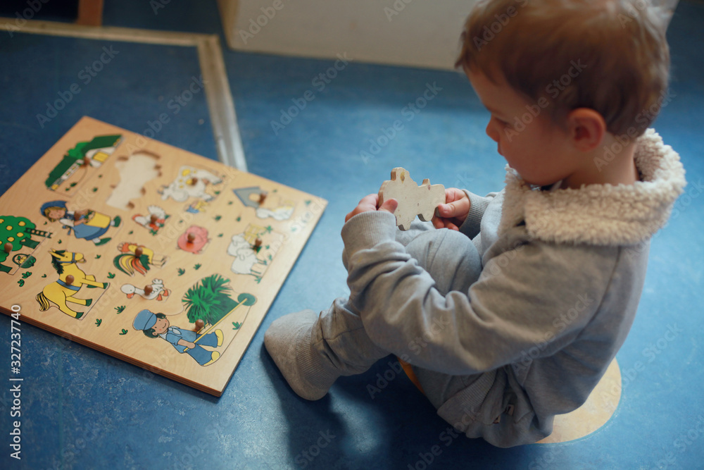 Little boy working with wooden puzzle in a classroom Stock Photo ...