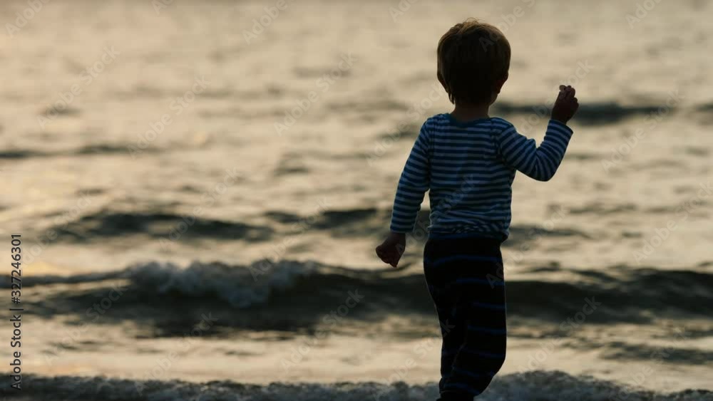 Amusing little child silhouette easy play at beach, throw with peddles ...