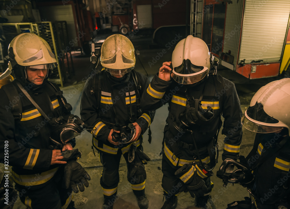 Group of firefighters with uniform inside the fire station preparing ...