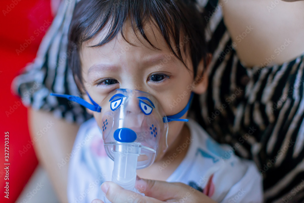Sick boy inhalation therapy by the mask of inhaler. Baby has asthma and ...