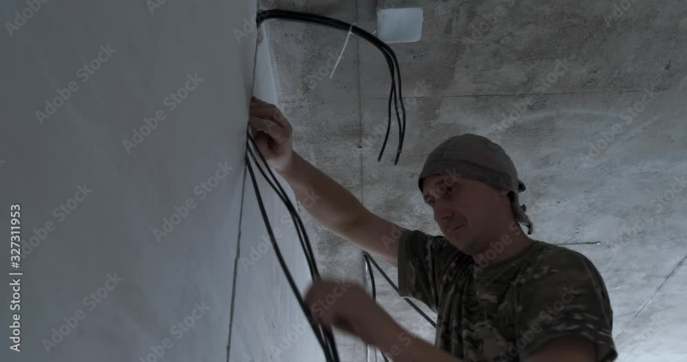 At construction site, male electrician attaches electric cables to ...