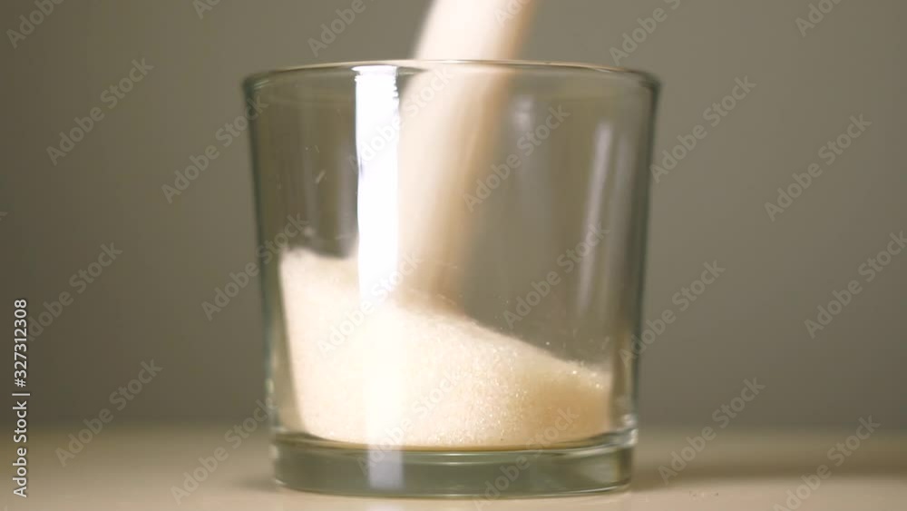 Regular white sugar in transparent glass with white reflection ...