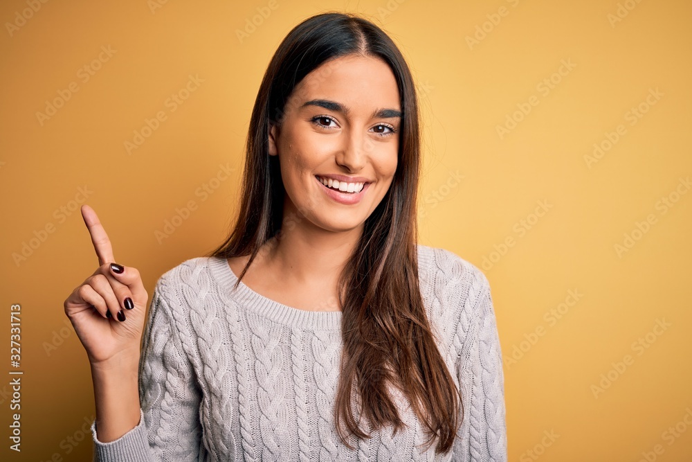 Young Beautiful Brunette Woman Wearing White Casual Sweater Over Yellow
