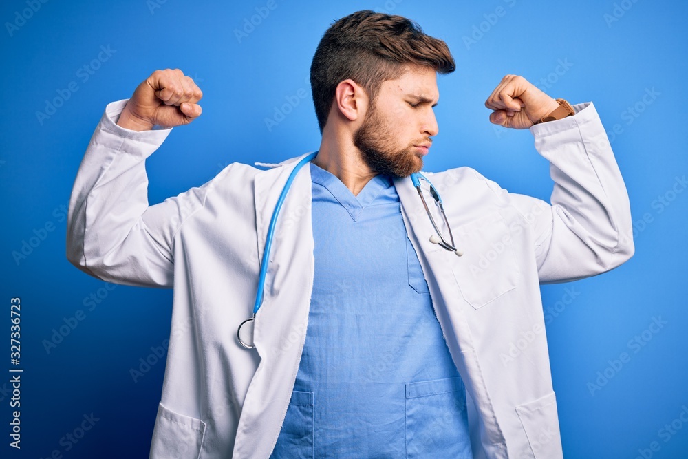 Young blond doctor man with beard and blue eyes wearing white coat and ...