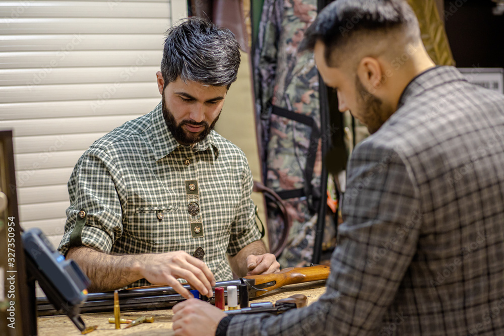 young customer and confident affable salesman discuss rifle power in ...