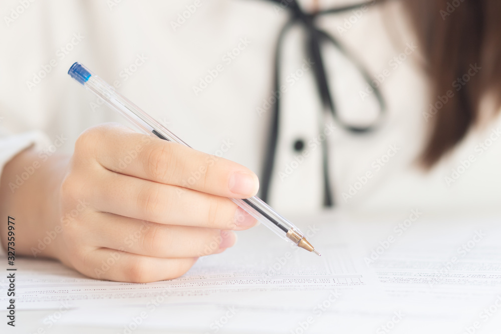 Female hands hold a pen, write on a sheet of paper, fill out a form on ...