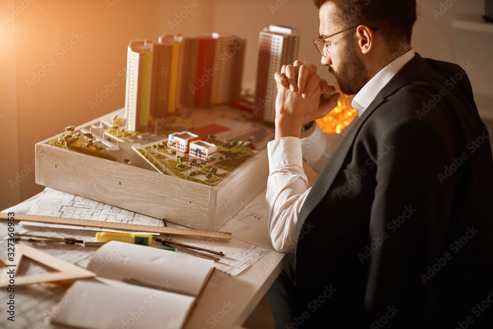 pensive architect working at office desk,sitting in front of the layout ...